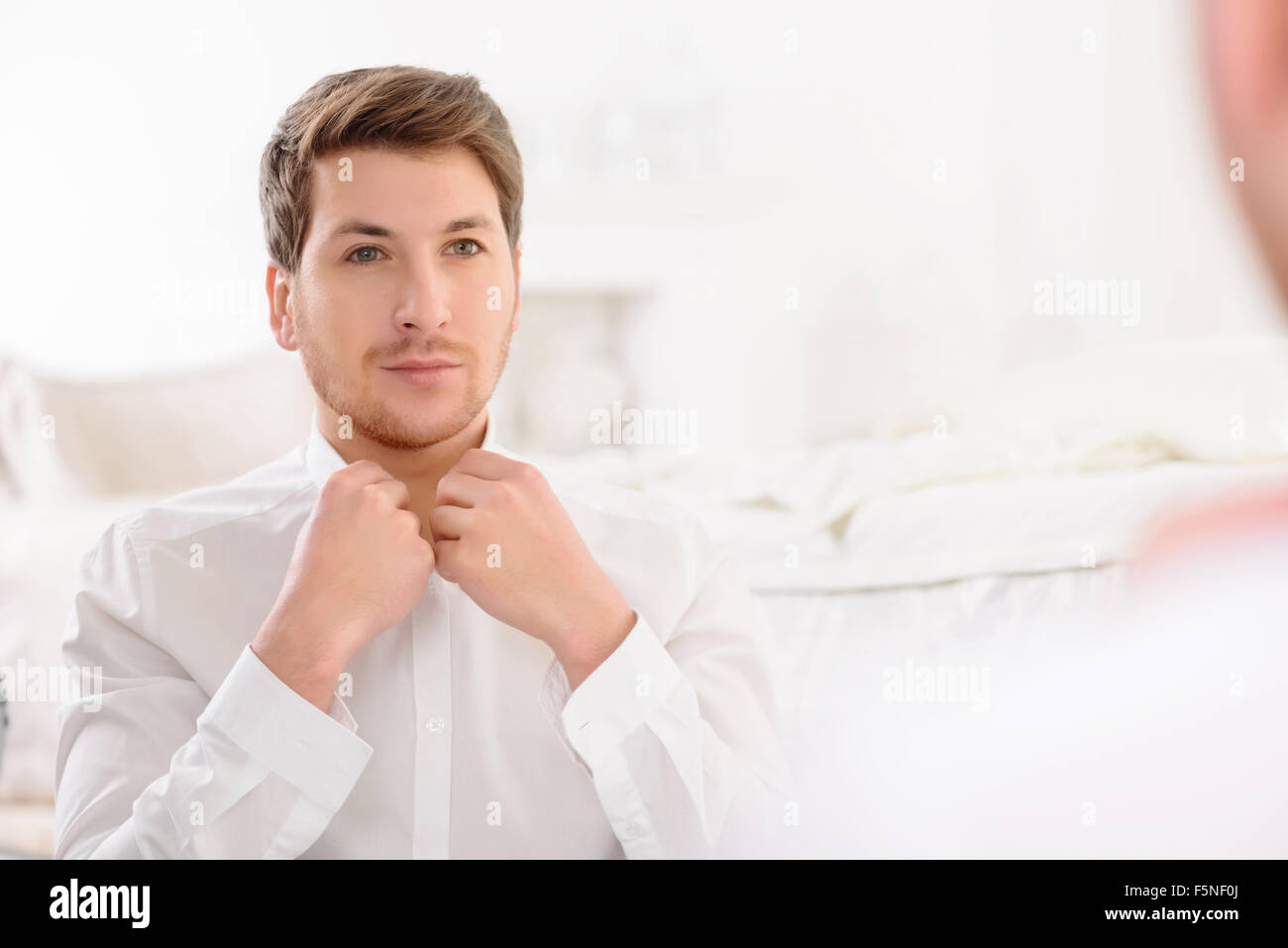 Young man in process of putting on a shirt Stock Photo - Alamy