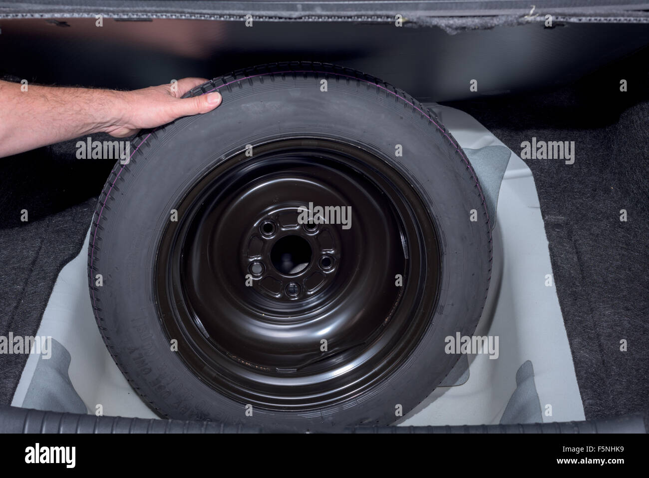 Removal demonstration of spare tire from trunk Stock Photo - Alamy