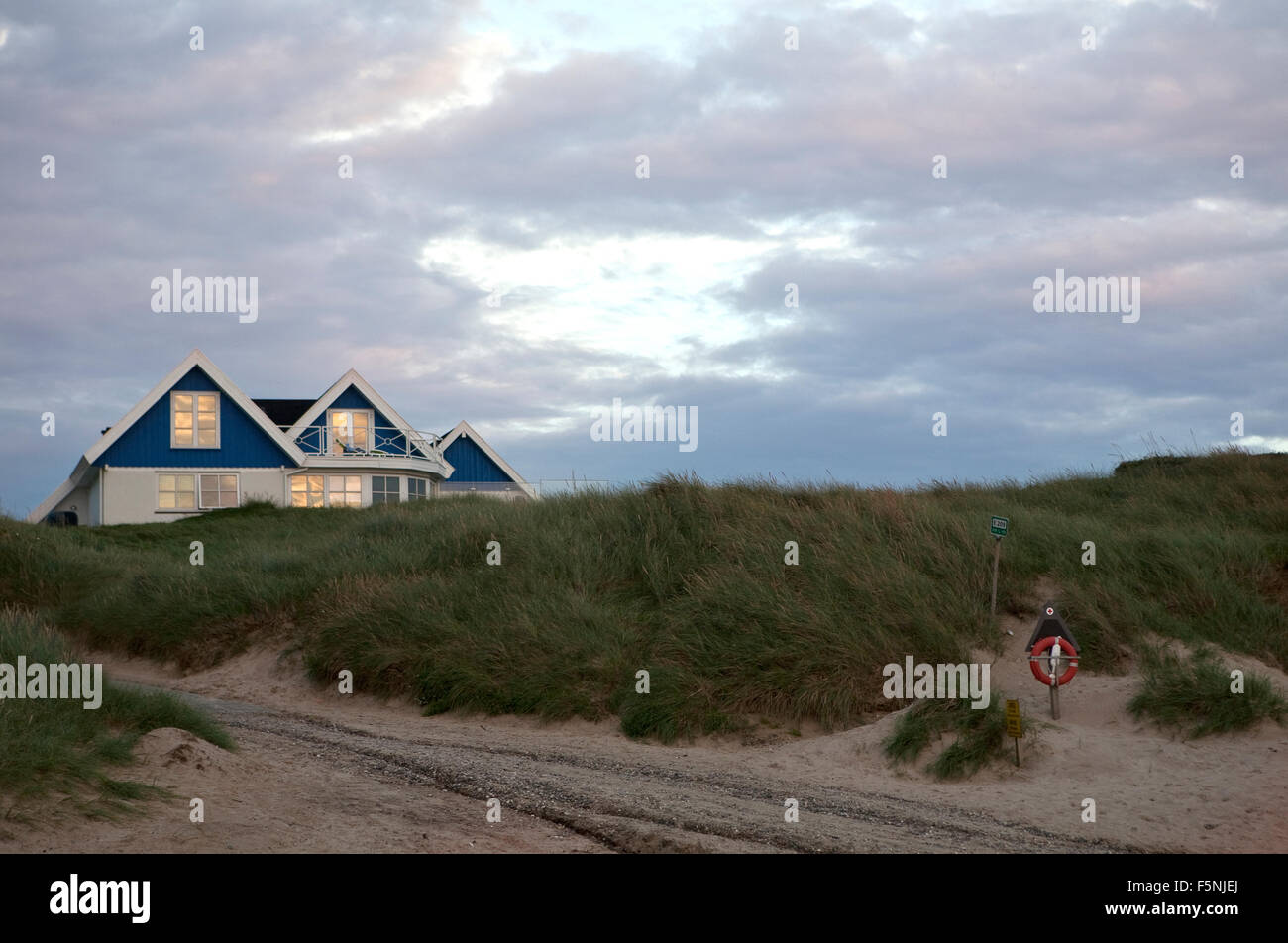 A summer cottage right on the beach is reflecting the sunset in its ...