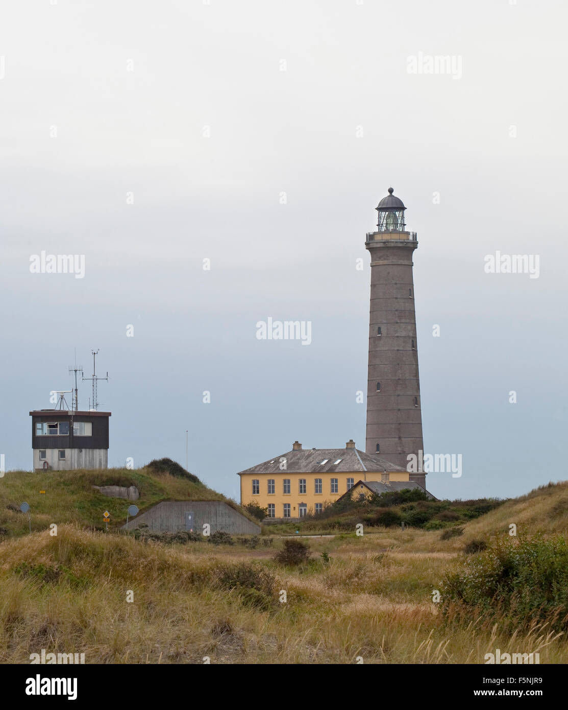 An unusually grey lighthouse stands beside a traditionally yellow ...