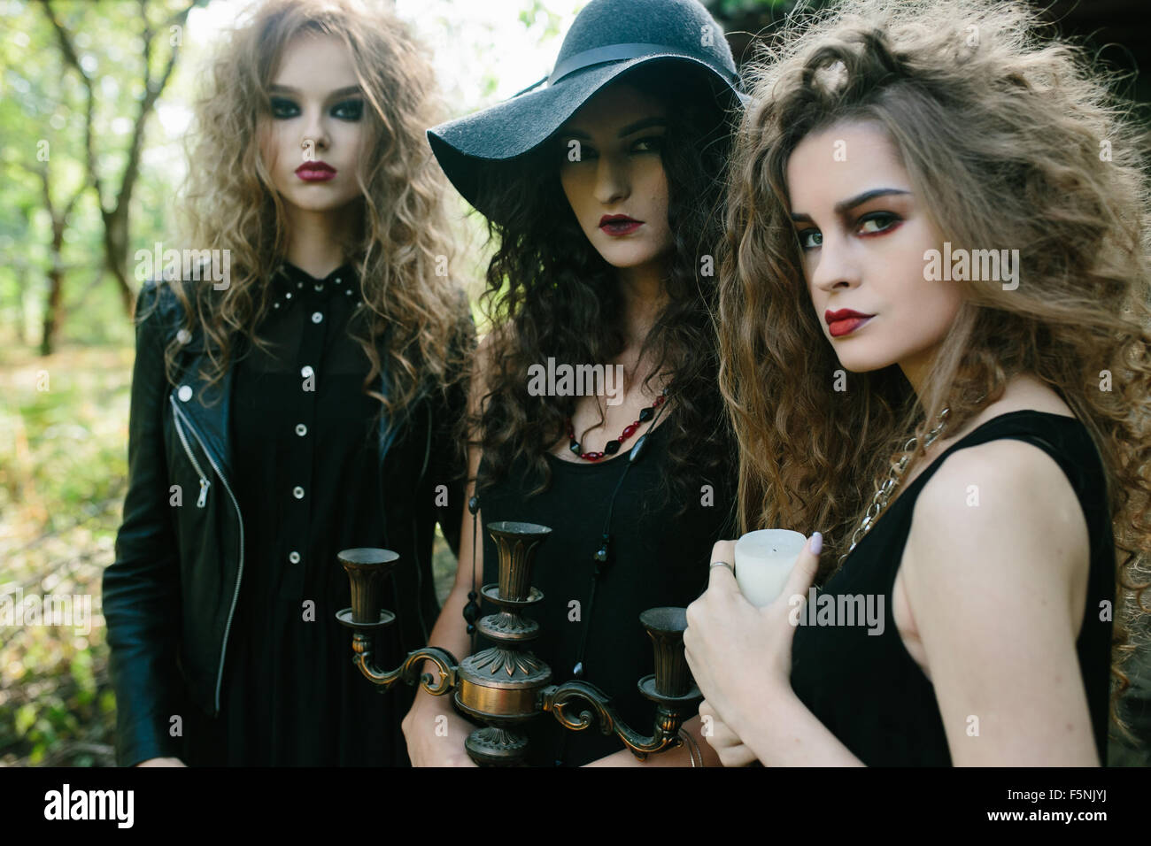three vintage women as witches, pose in front of an abandoned building ...