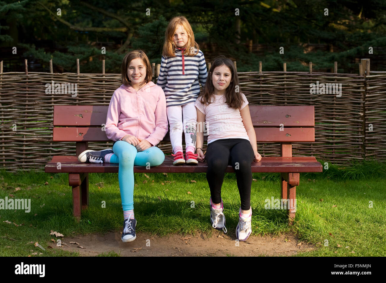 Gathered on a Bench. Three sisters are posing comfortably on a bench ...