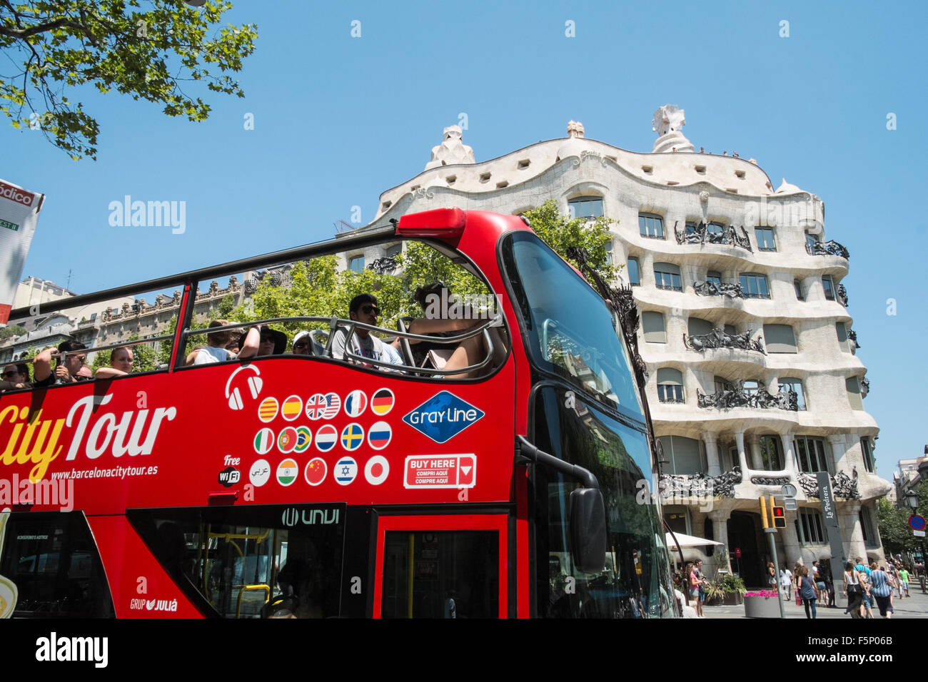 Tour bus passing La Pedrera designed by architect Antoni Gaudi ...