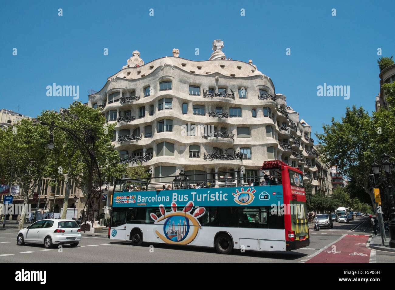 Tour bus passing La Pedrera designed by architect Antoni Gaudi ...