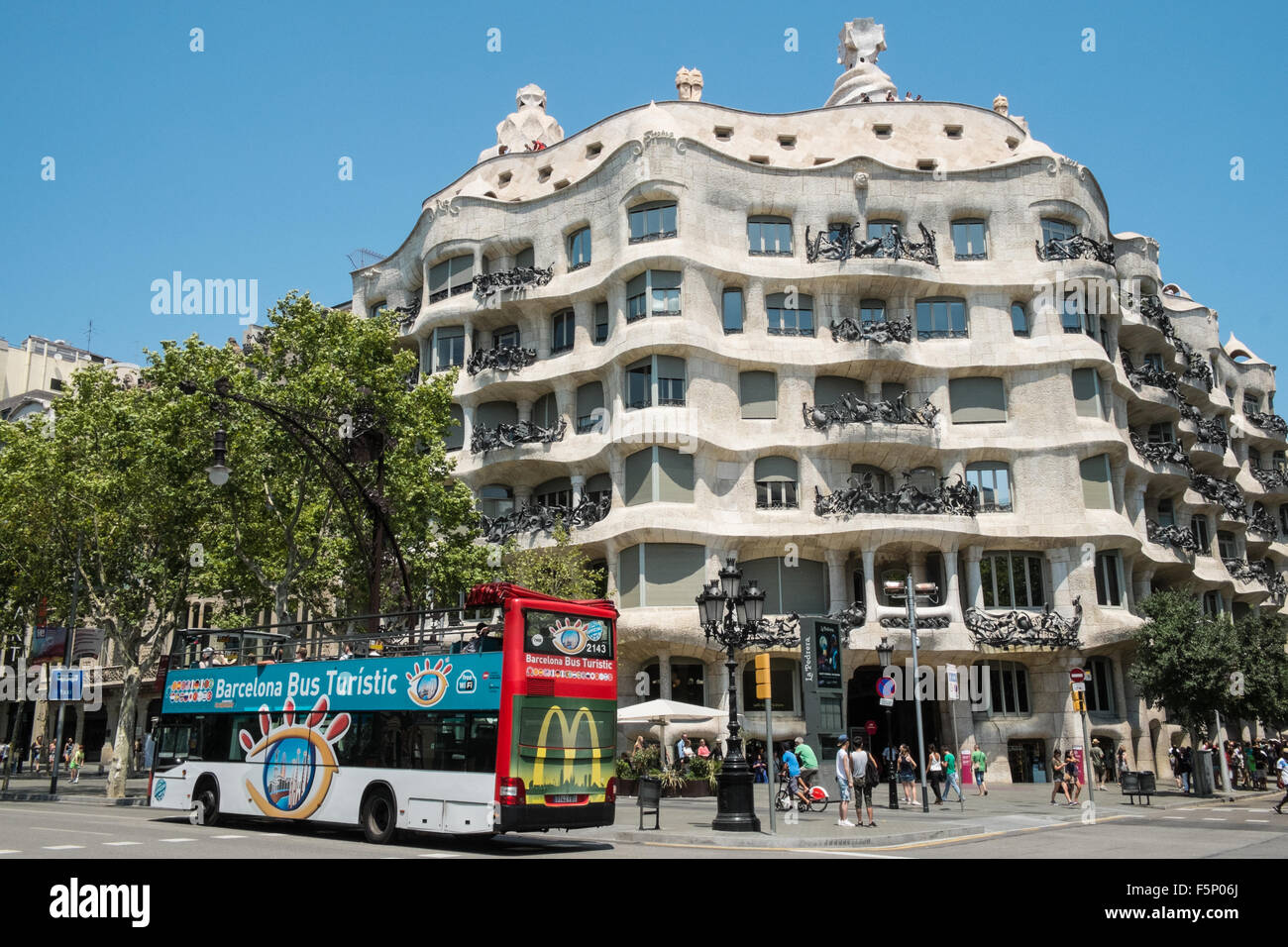 Tour bus passing La Pedrera designed by architect Antoni Gaudi ...