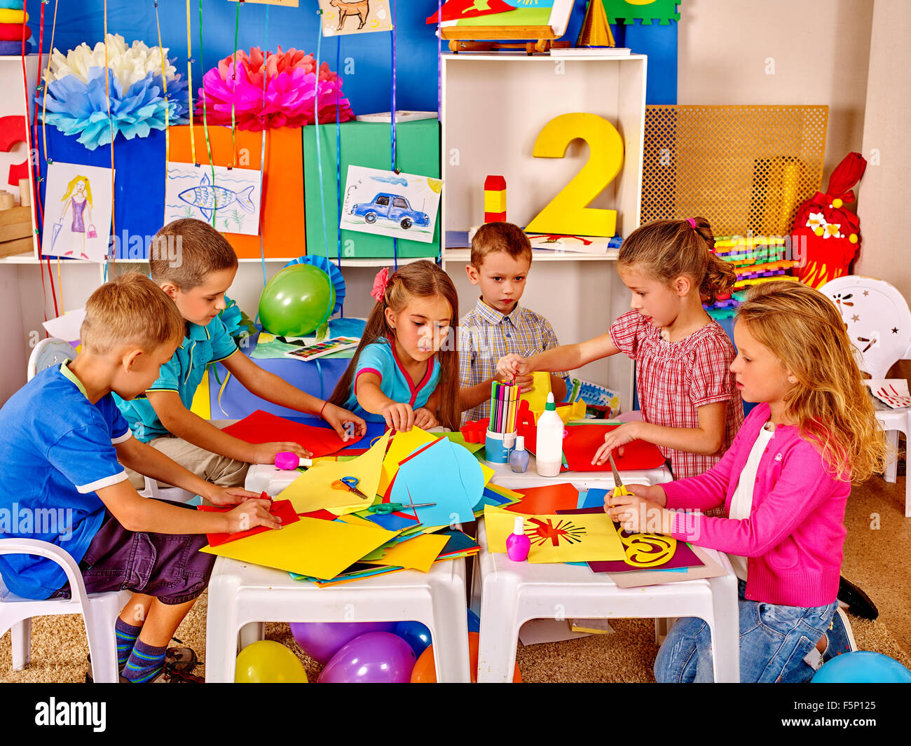 Kids holding colored paper and glue on table in kindergarten Stock ... Kids holding colored paper and glue on table in kindergarten Stock ...