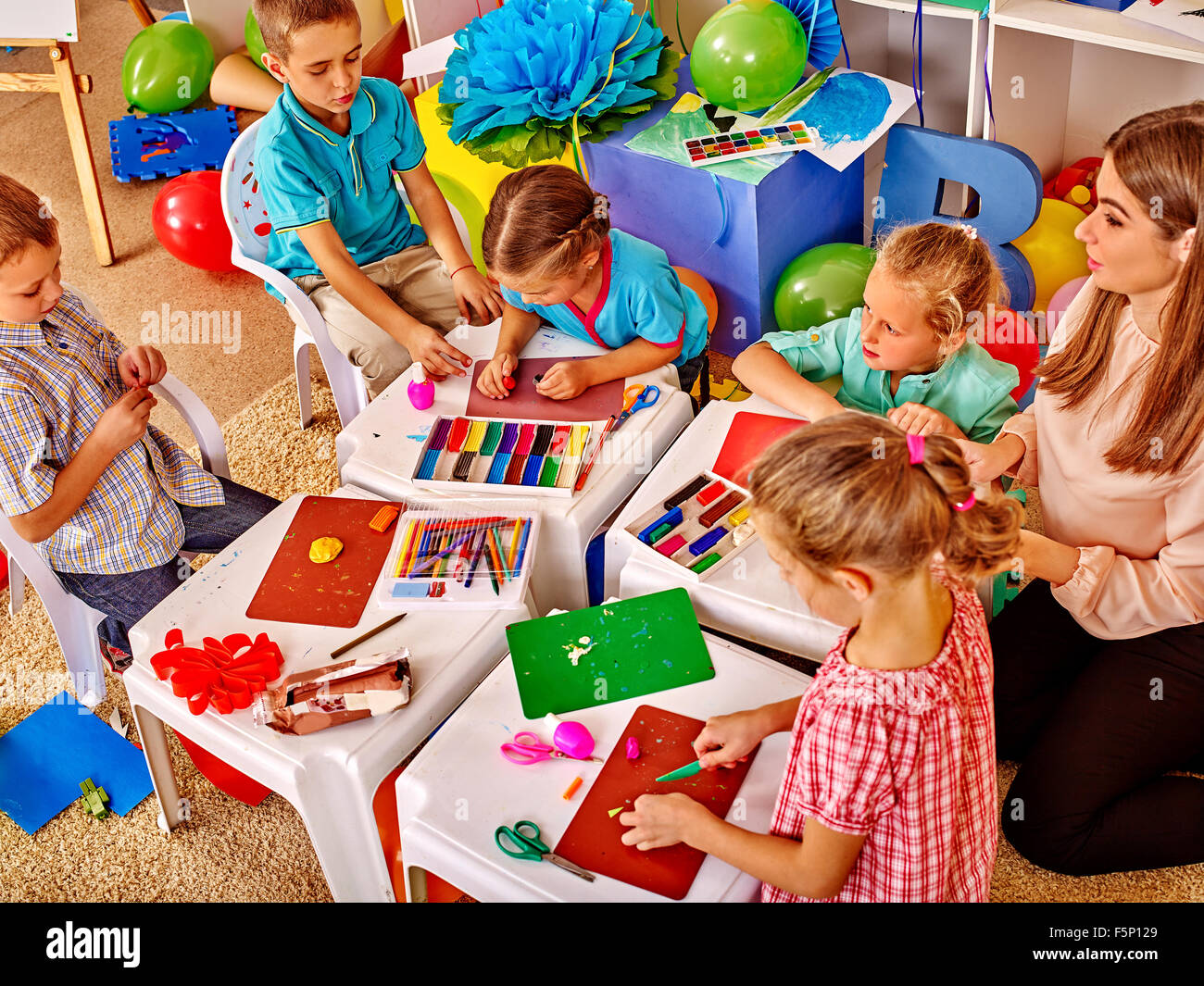 Kids holding colored paper and glue on table in kindergarten Stock ... Kids holding colored paper and glue on table in kindergarten Stock ...