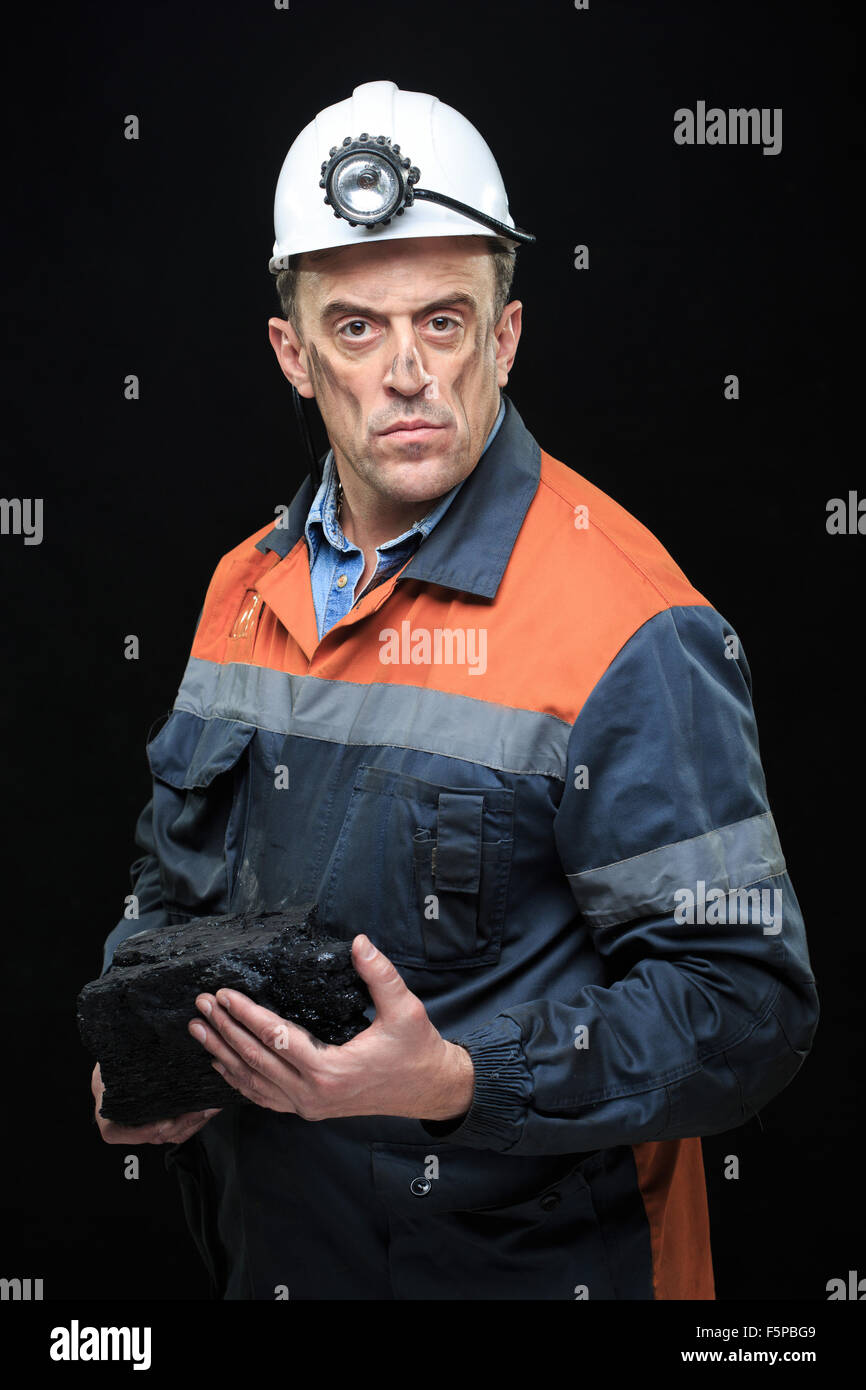 Coal miner showing lump of coal with thumbs up against a dark Stock ...