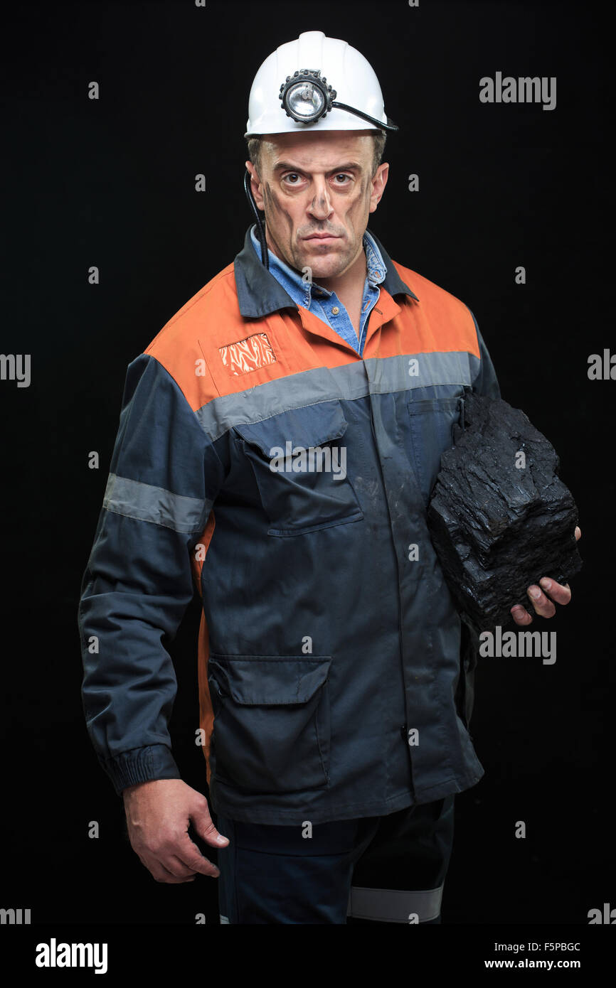 Coal miner showing lump of coal with thumbs up against a dark Stock ...