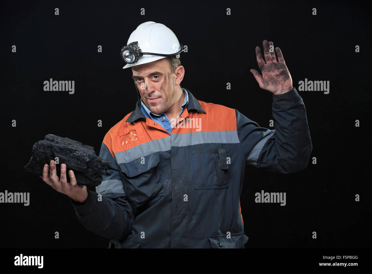 Coal miner showing lump of coal with thumbs up against a dark Stock ...