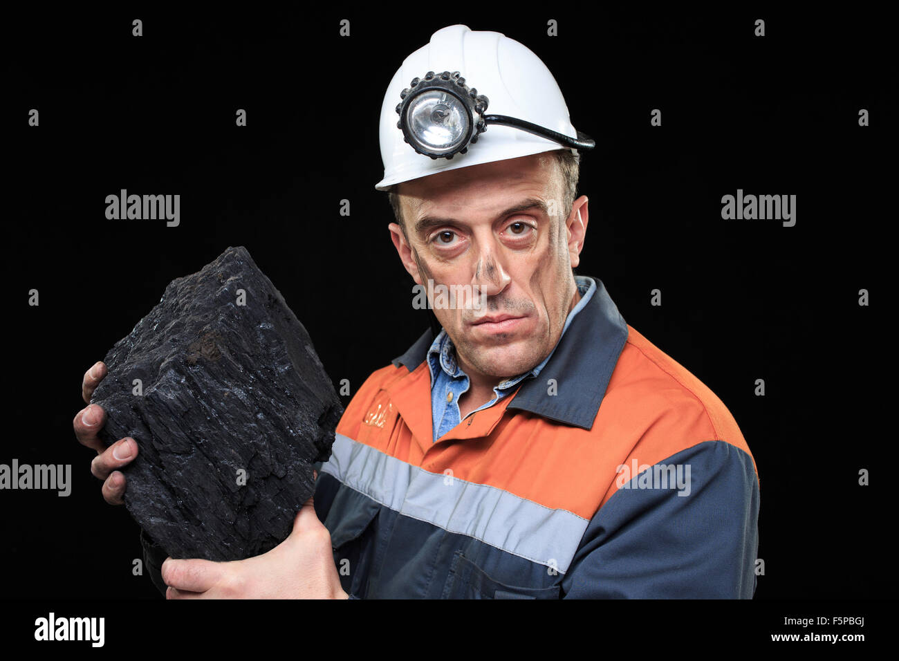 Coal miner showing lump of coal with thumbs up against a dark Stock ...