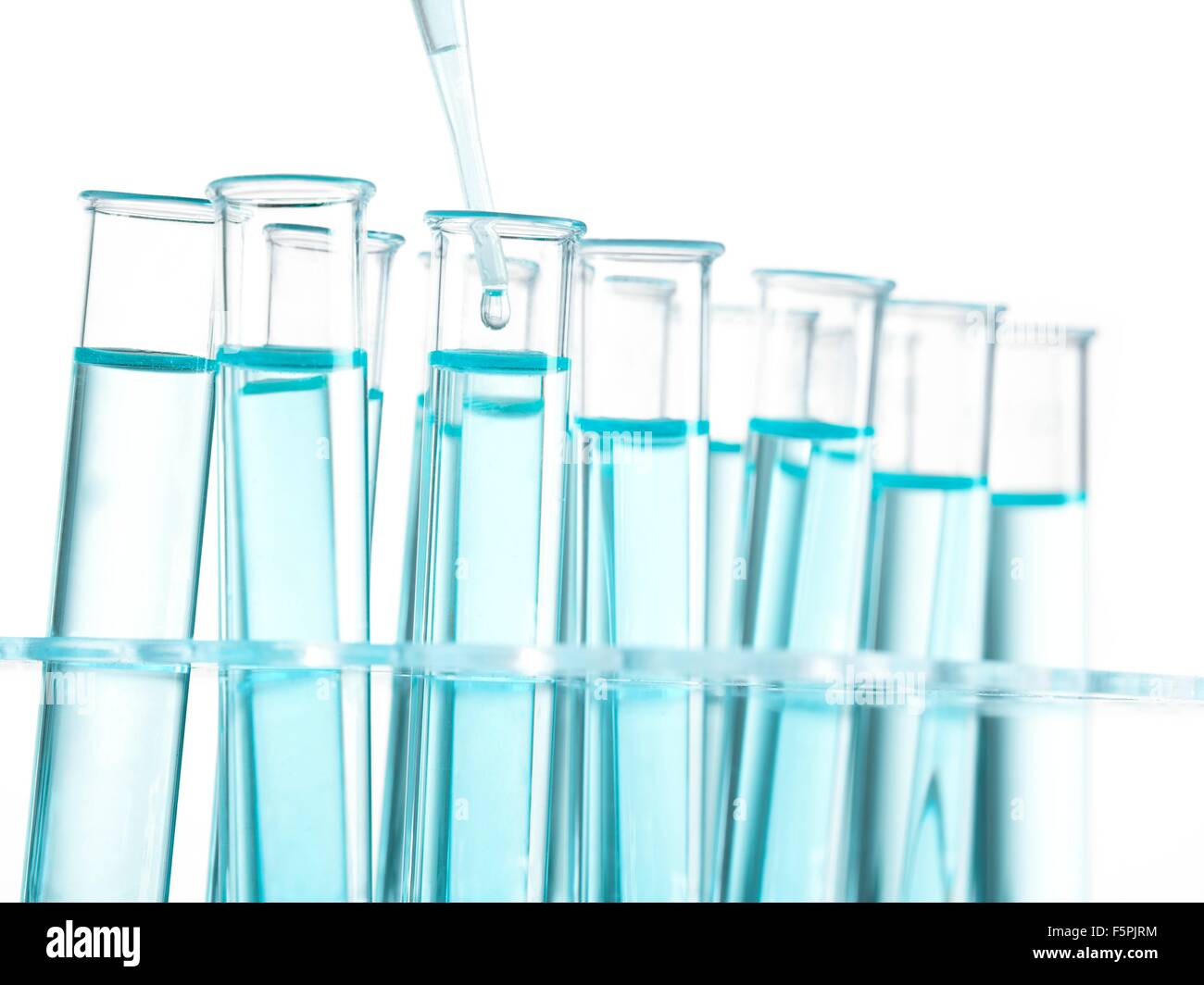 Pipette dripping liquid into test tubes in a rack Stock Photo - Alamy