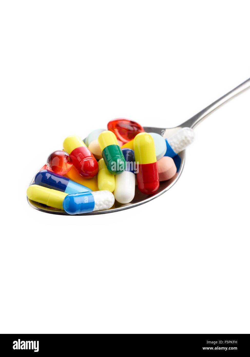 Spoon full of tablets and capsules against a white background Stock ...