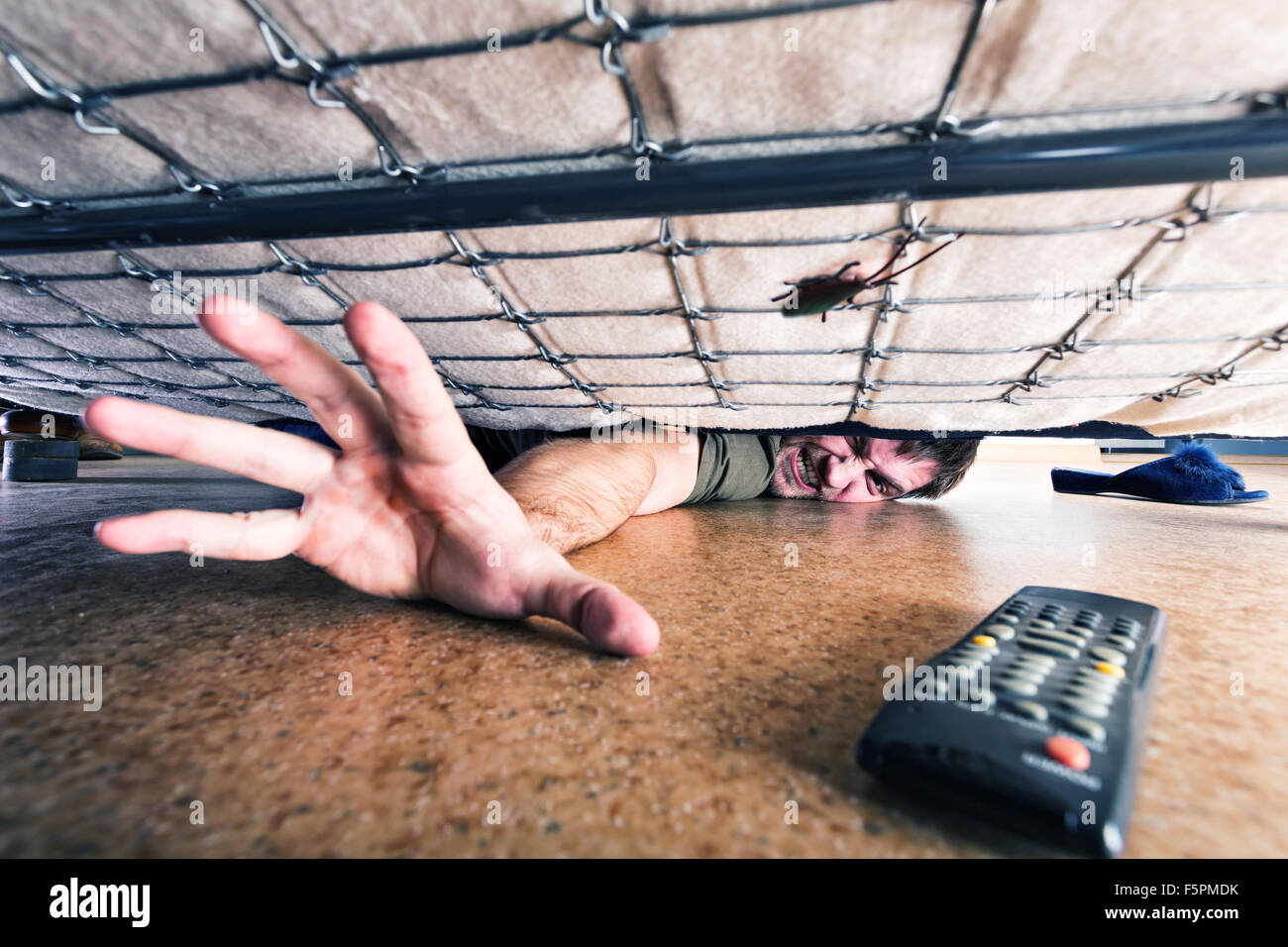 Man trying to get something under the couch Stock Photo - Alamy