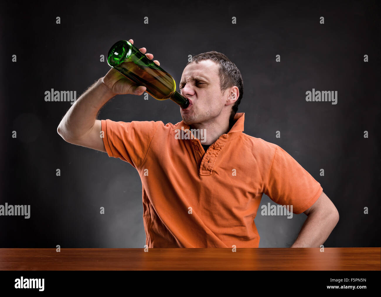 Adult man drinks alcohol over gray Stock Photo - Alamy