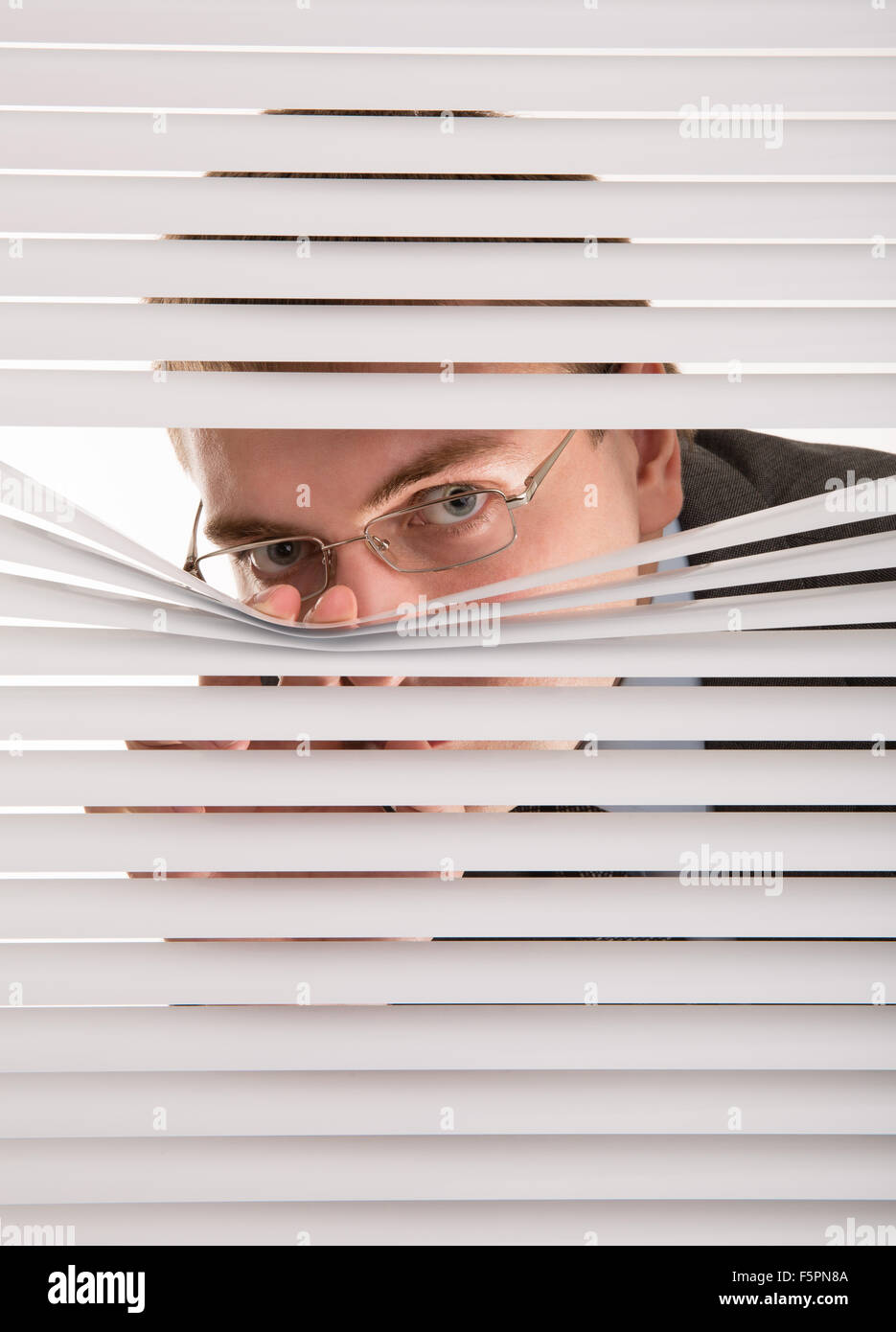 A young man looking through window blinds Stock Photo - Alamy