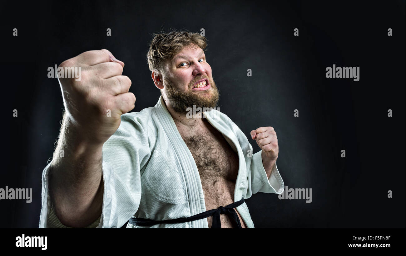 Aggressive bearded karate fighter in white kimono over grey Stock Photo ...