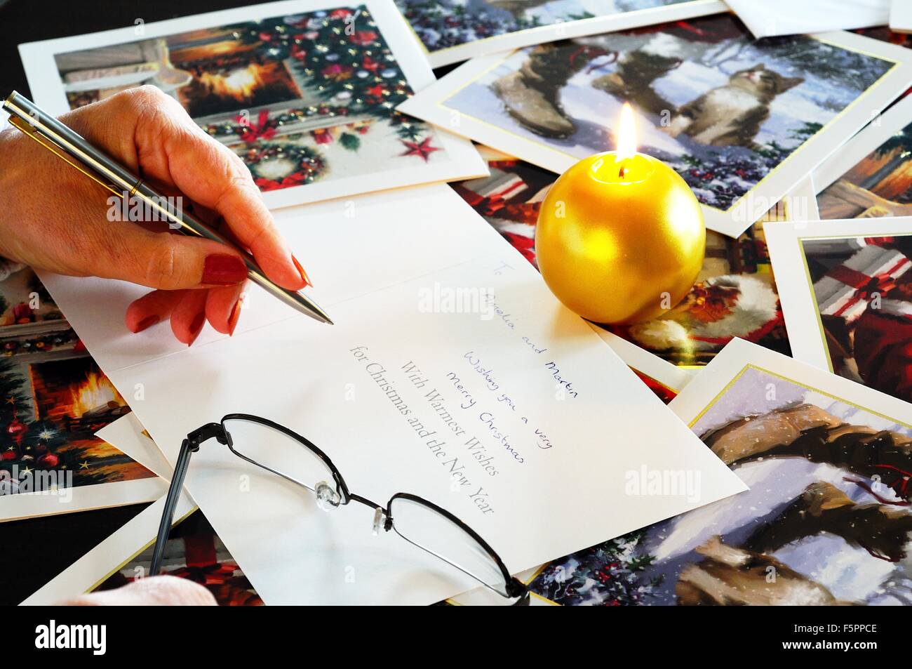 Writing Christmas cards by candlelight with cards scattered on the ...
