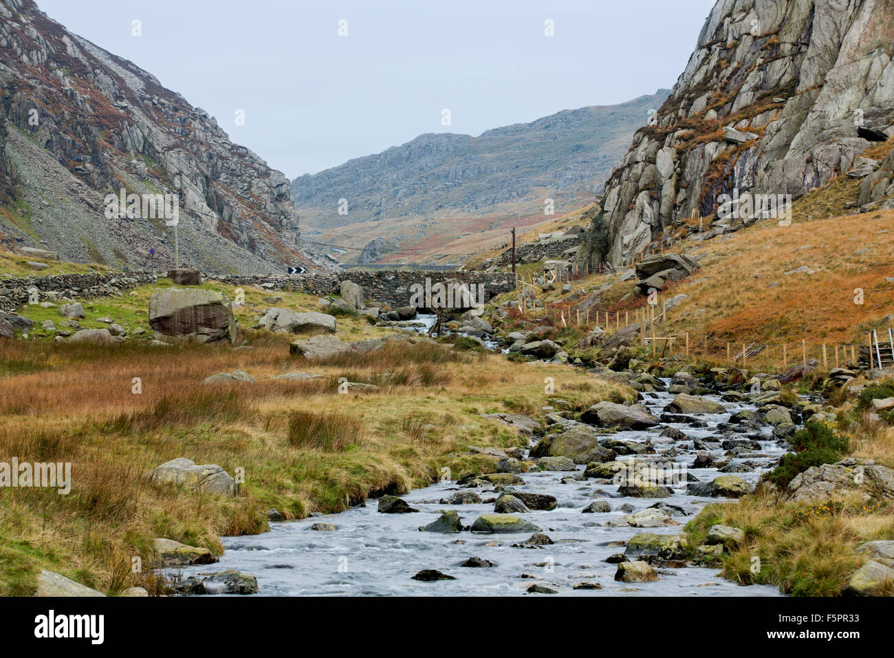 Snowdonia mountain pass with stream in a steep valley. Old quaint stone ...