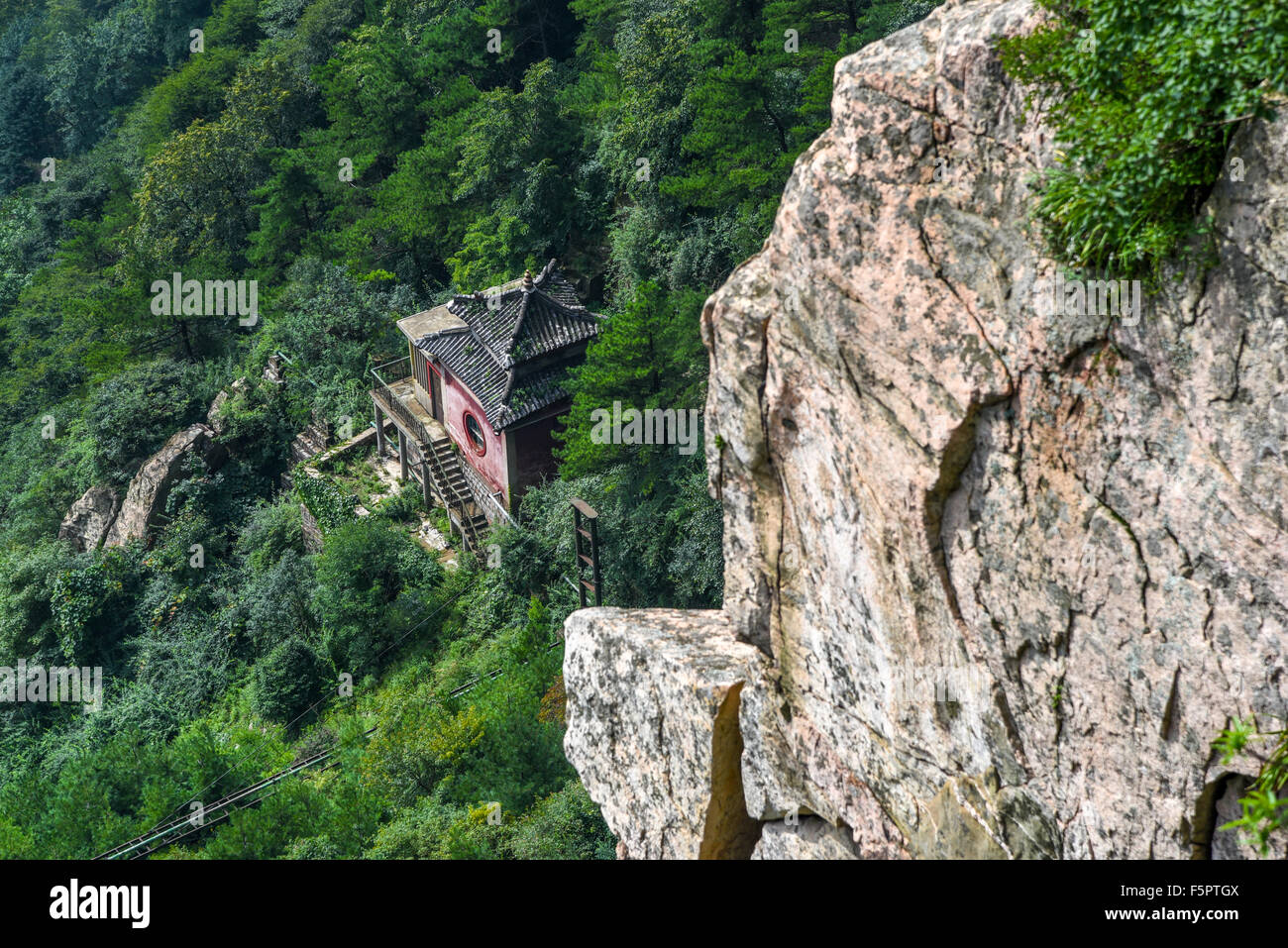 A red temple hidden in trees and cliffs Stock Photo - Alamy