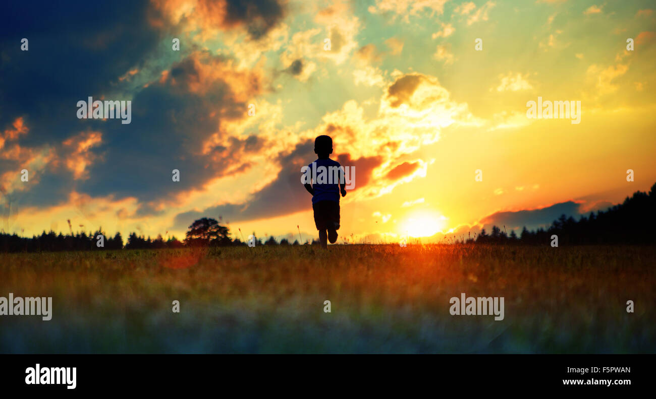 Cheerful child running towards the sunset Stock Photo - Alamy