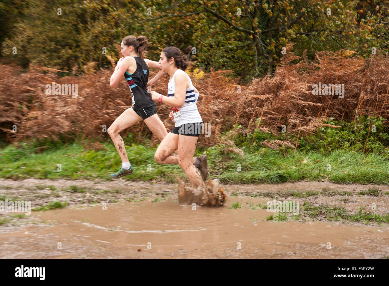 blond young lady runner coated in rain and mud facing elements in cross ...