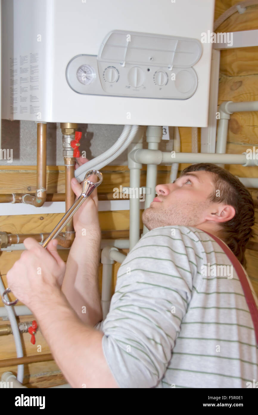 Plumber at work. Servicing gas boiler Stock Photo - Alamy