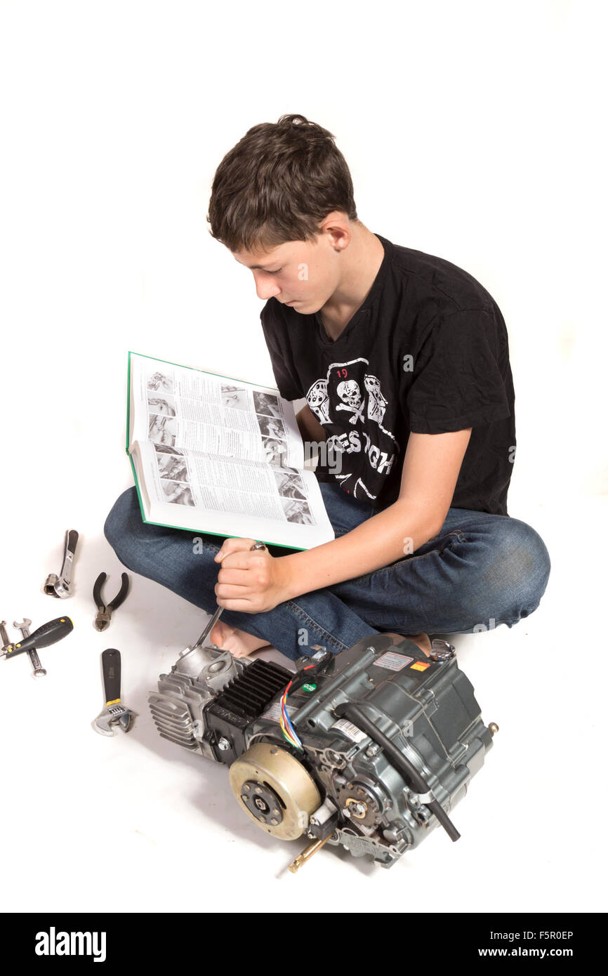 Teenage Boy Fixing an Engine using a manual Stock Photo - Alamy