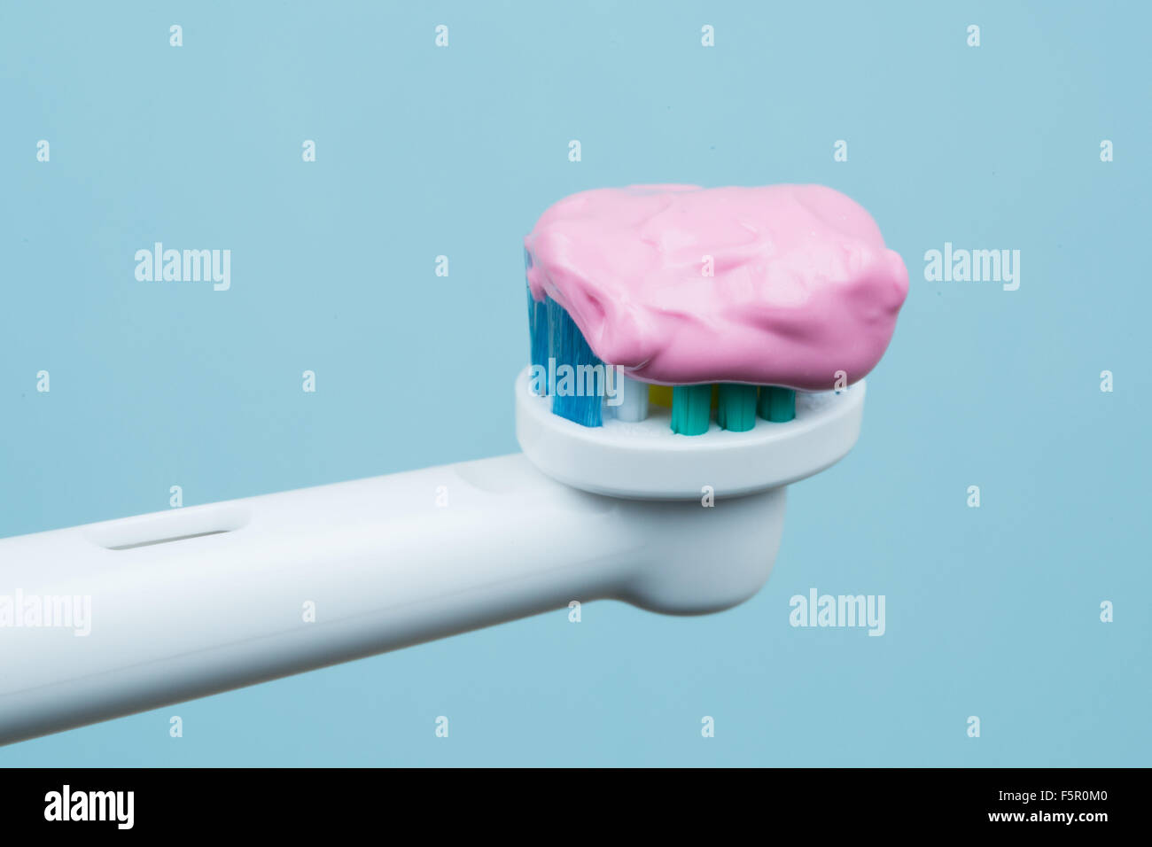 An electric toothbrush on a blue background with pink toothpaste Stock ...