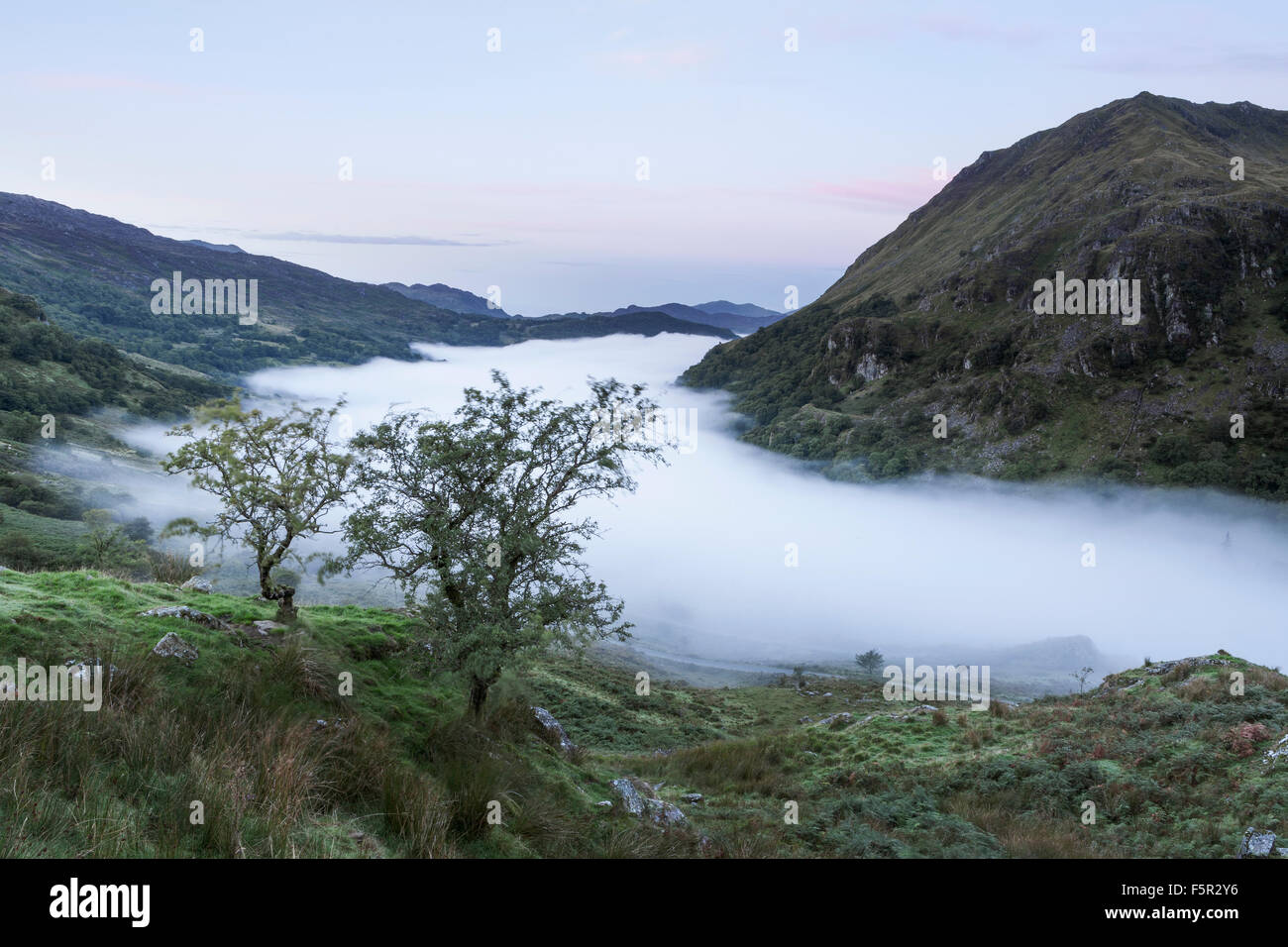 Fog hangs in the valley over Llyn Gwynant, Snowdonia before the sun ...