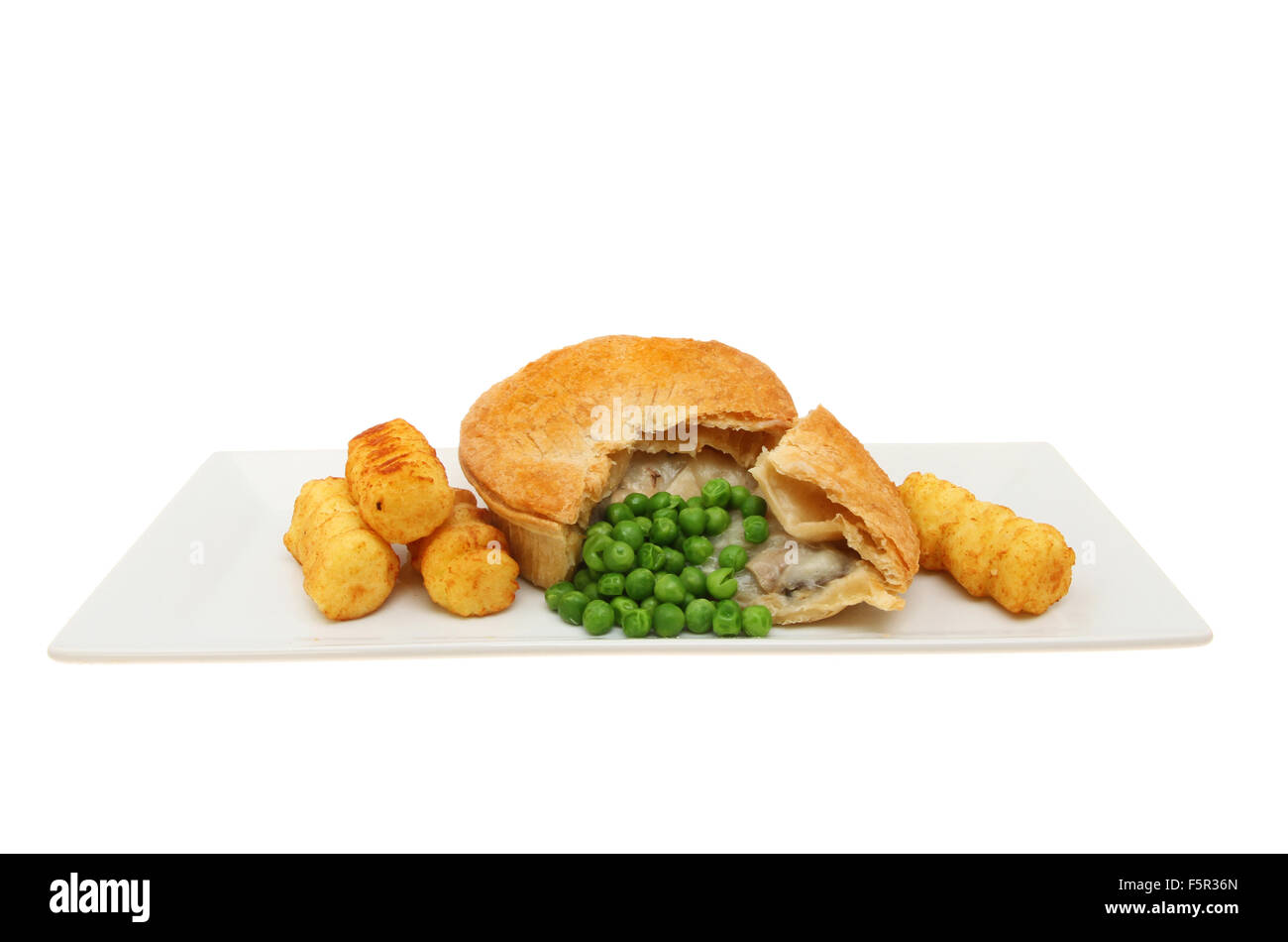 Chicken pie with croquette potatoes and peas on a rectangular plate ...