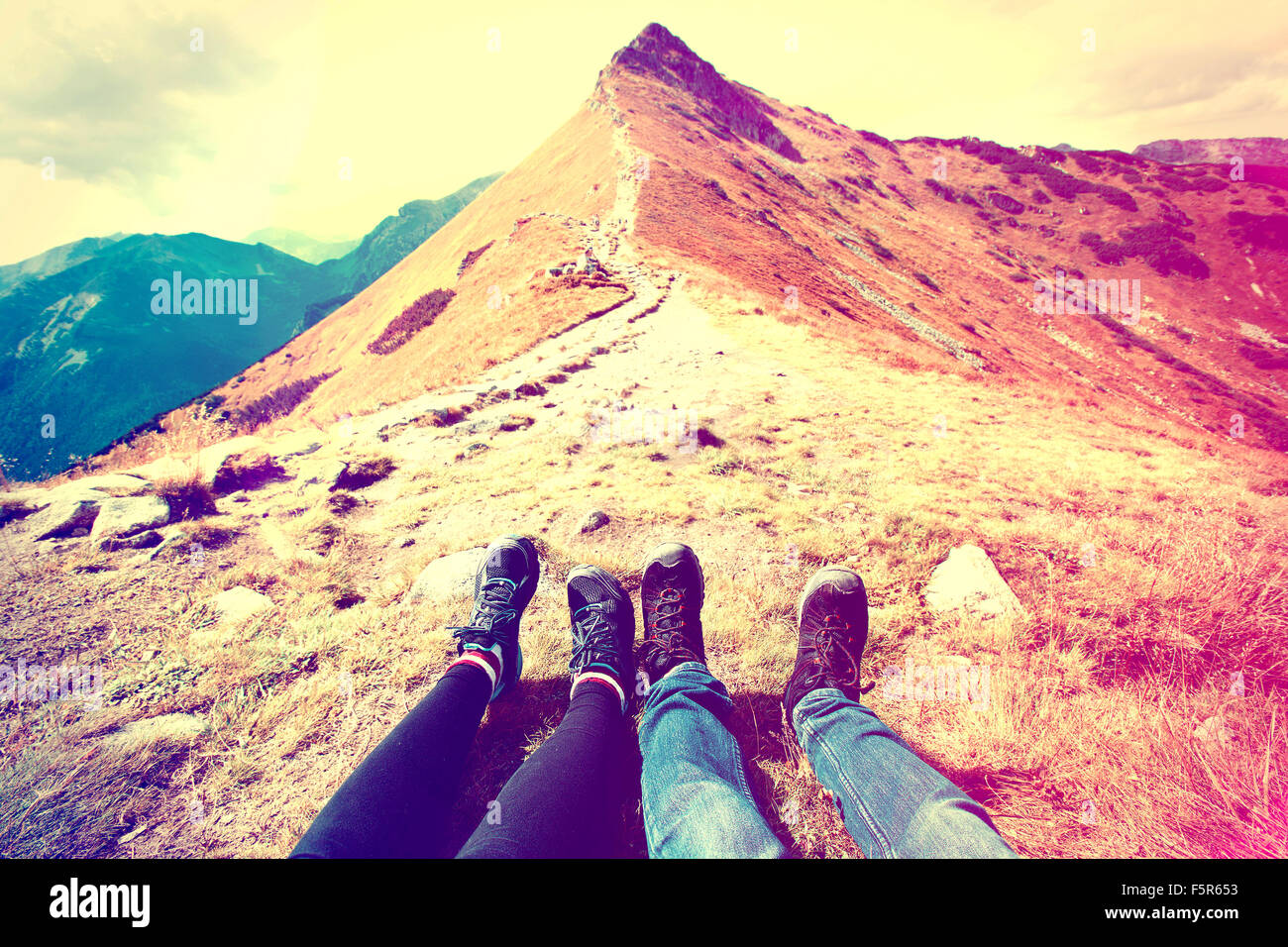 Tourism in mountains. A couple of tourists rest on the mountain path ...