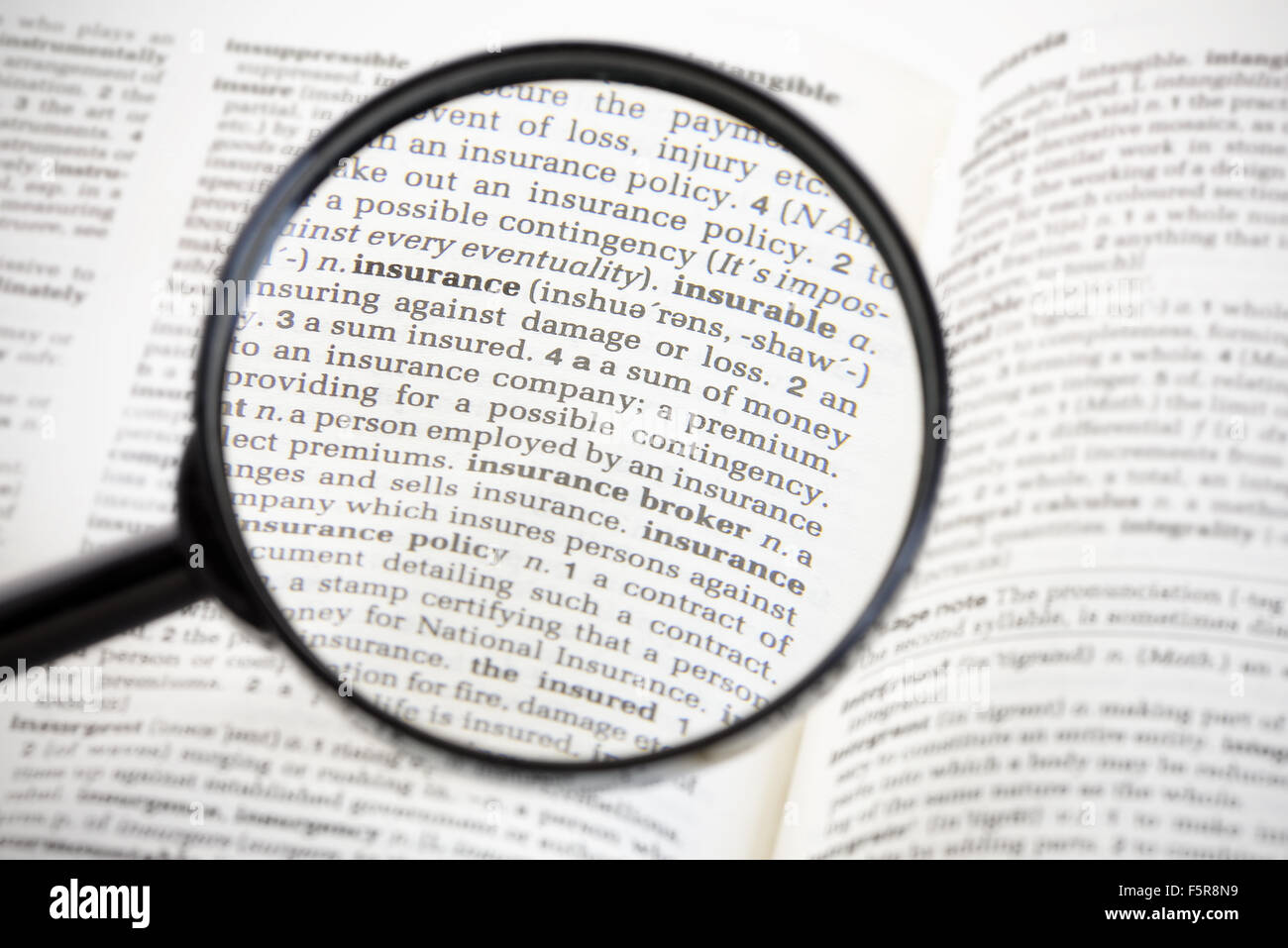 Magnifying glass focussed on the word 'insurance' on the page of a ...