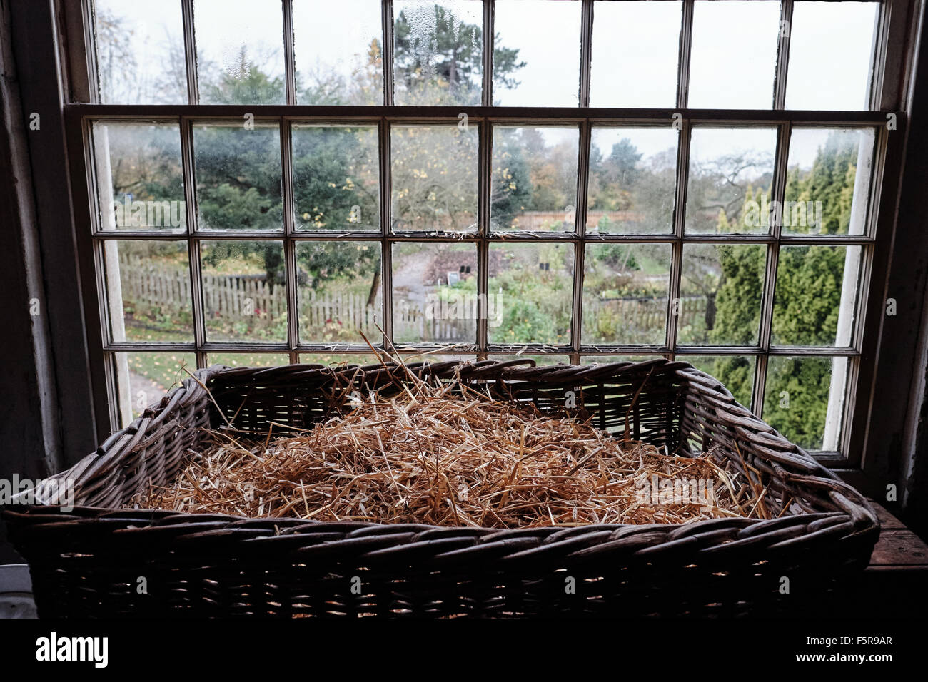 Basket of straw in front of a window Stock Photo - Alamy