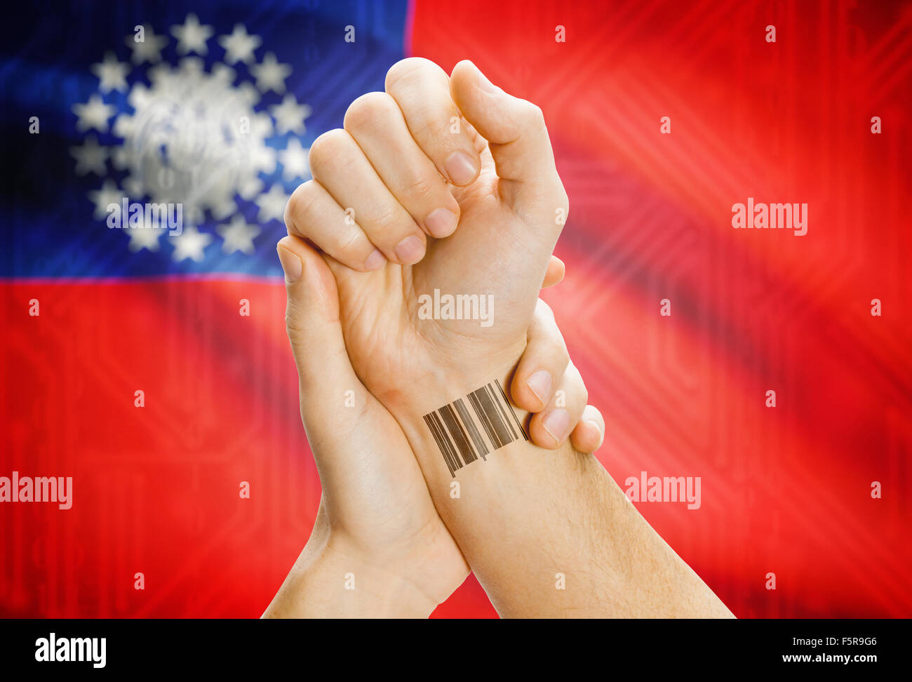 Barcode ID number on wrist of a human and national flag on background ...