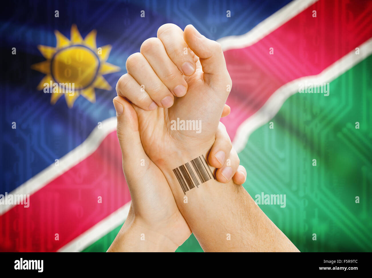 Barcode ID number on wrist of a human and national flag on background ...