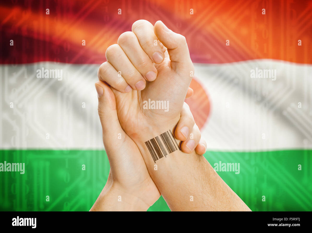 Barcode ID number on wrist of a human and national flag on background ...