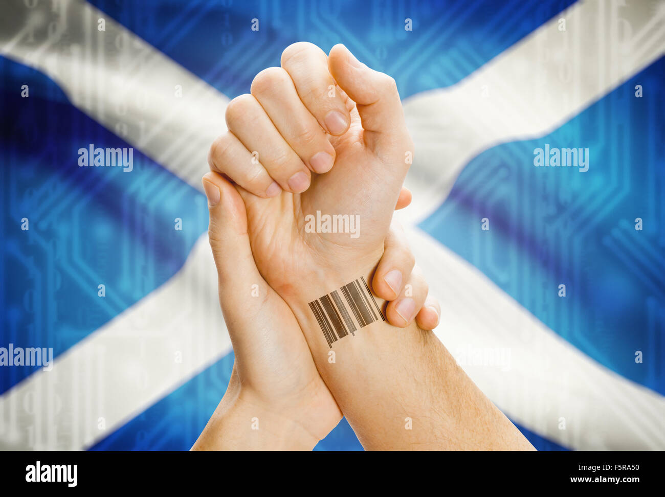 Barcode ID number on wrist of a human and national flag on background ...