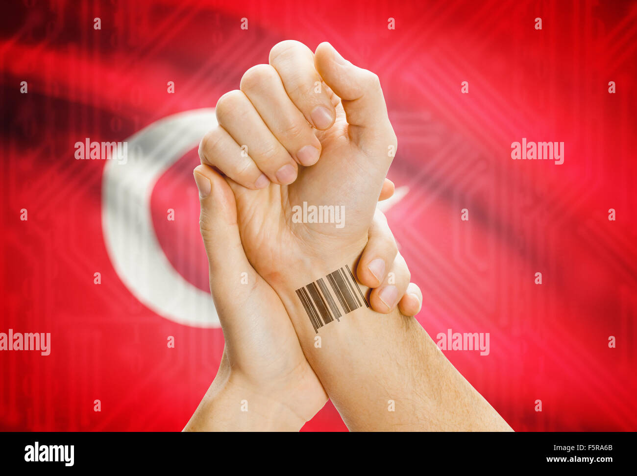 Barcode ID number on wrist of a human and national flag on background ...