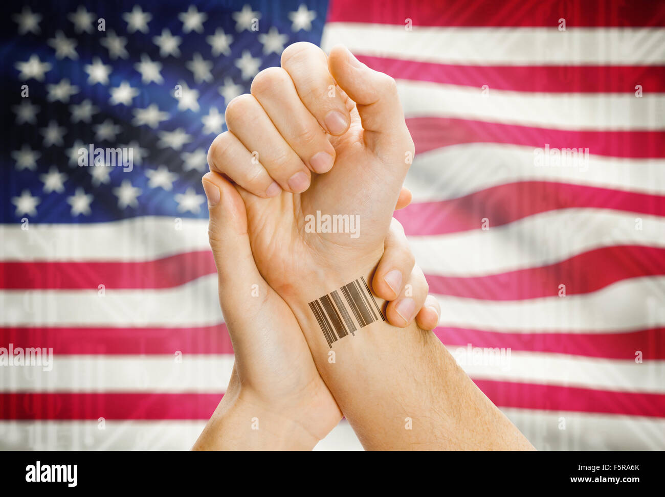 Barcode ID number on wrist of a human and national flag on background ...
