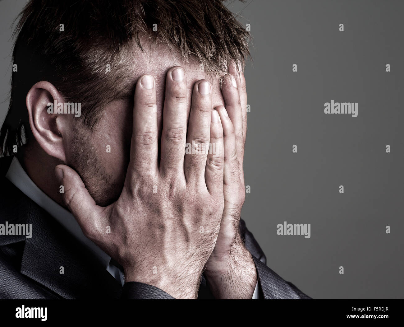Exhausted sad businessman covering his face by hands Stock Photo - Alamy