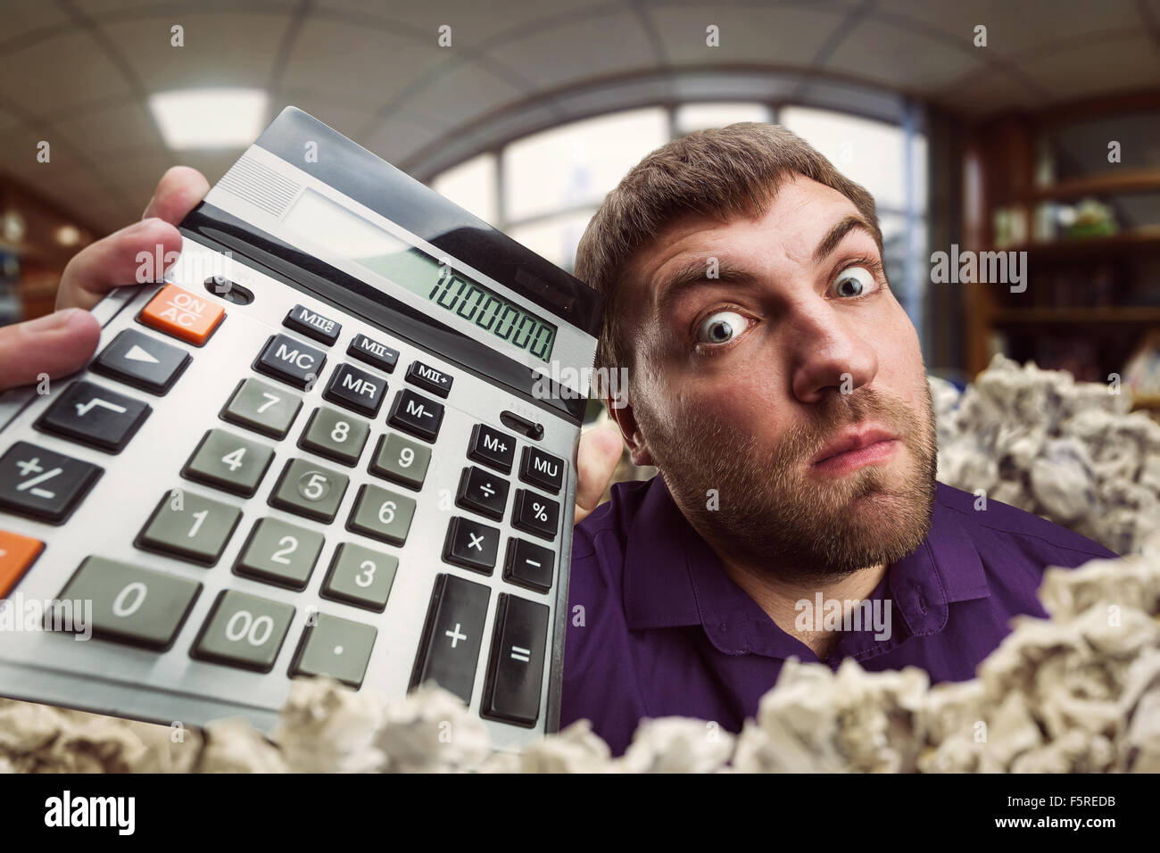 Surprised accountant holds calculator with a big total Stock Photo - Alamy