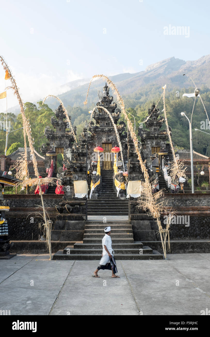A worshipper at the Pasar Agung Temple with the summit of the volcano ...