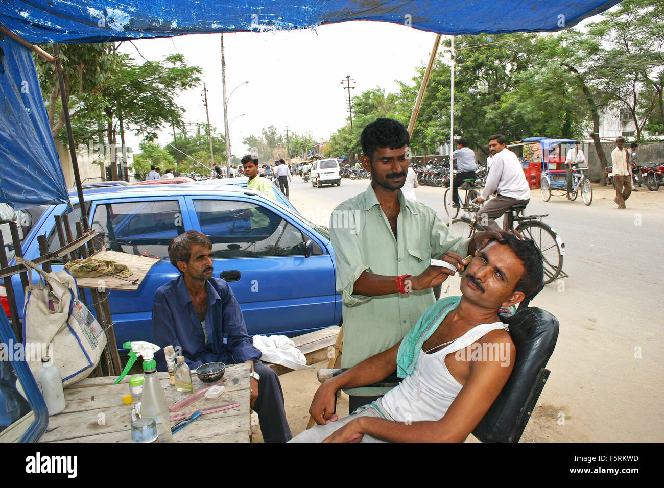 Delhi,India - July 9,2004: A barber shaving a customer at the road side ...