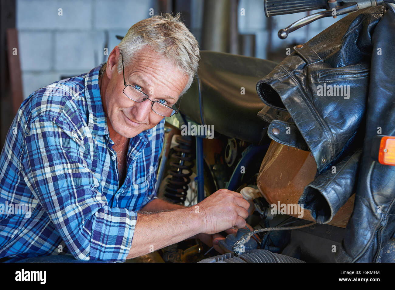 Mature aged man making adjustments to his motorbike Stock Photo - Alamy