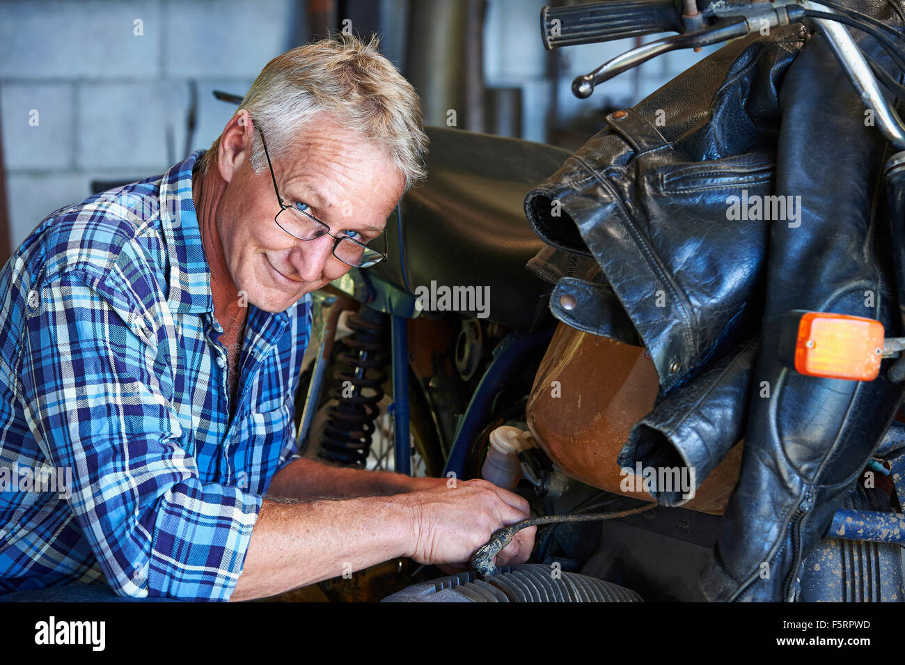 Mature aged man making adjustments to his motorbike Stock Photo - Alamy