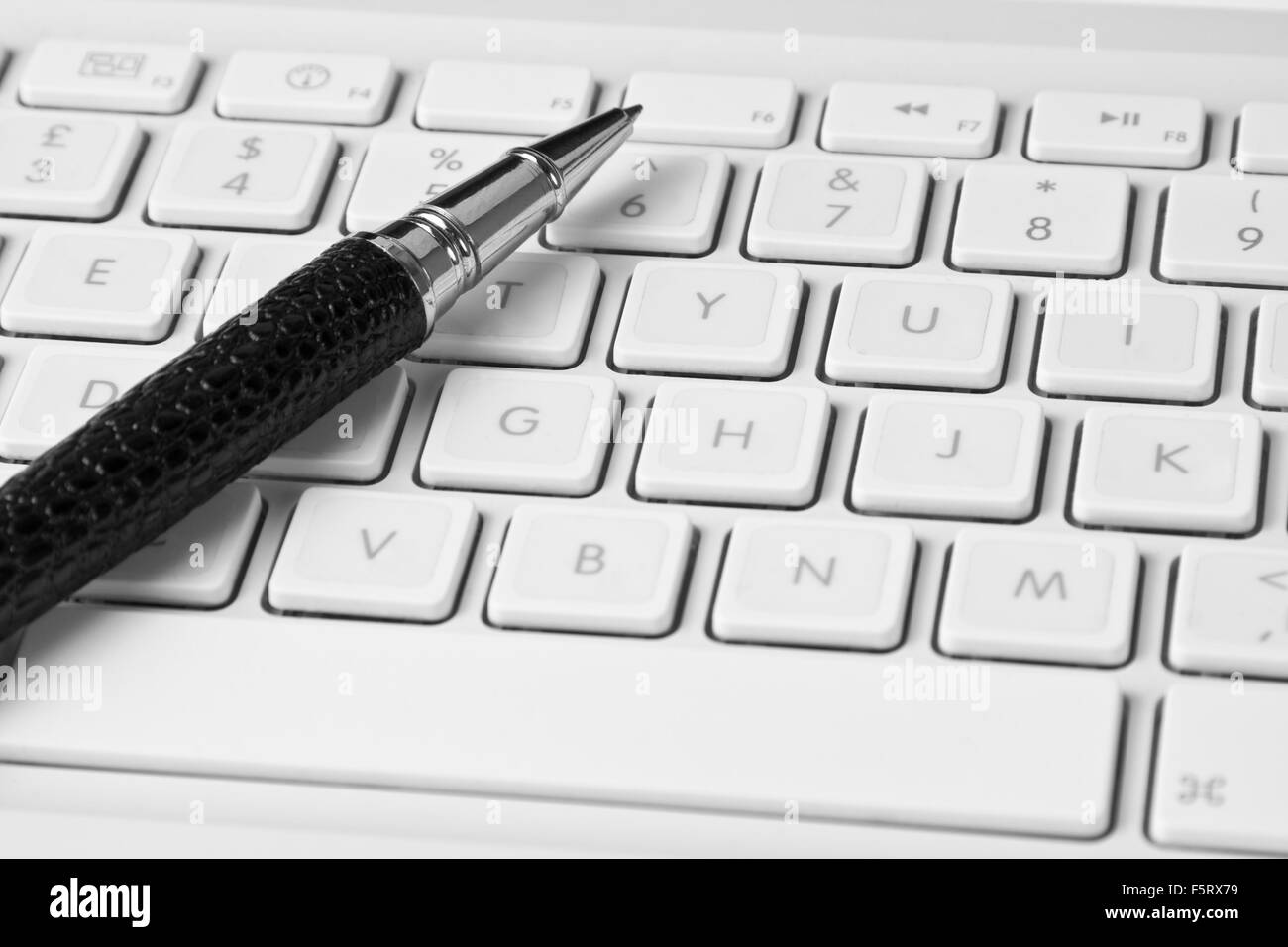 Pen on keyboard Stock Photo - Alamy