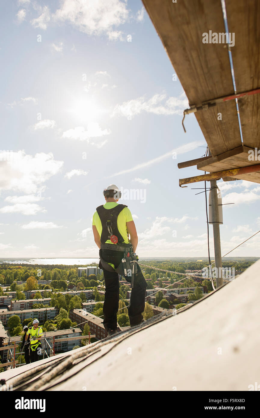 Rear view of two construction workers working at construction site hi ...