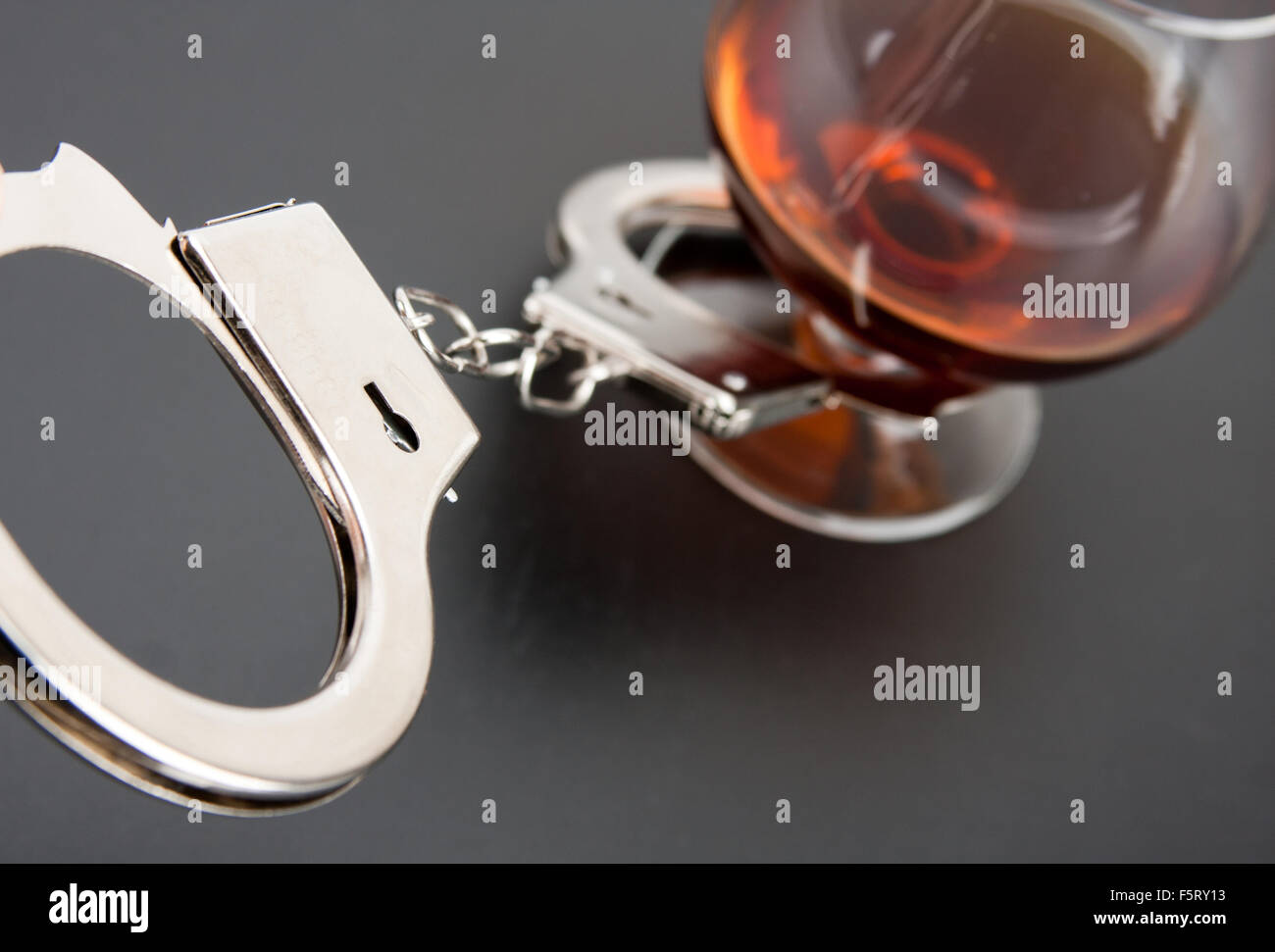 Close-up of handcuffs lock with glass of alcohol on background Stock ...