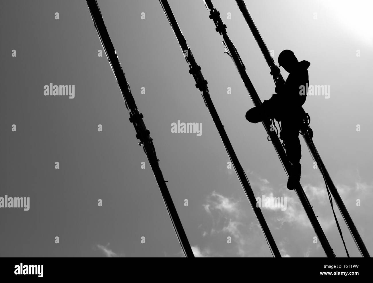 Silhouette of construction climber on suspension bridge Stock Photo - Alamy